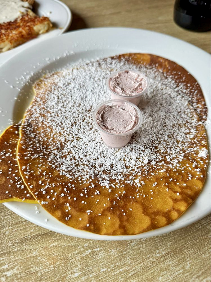 A golden pancake dusted with powdered sugar snow. The butter cups are like tiny treasure chests of melty goodness.