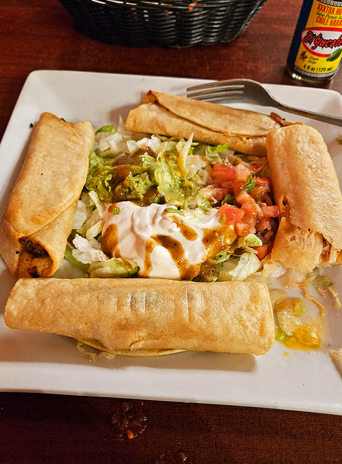 Four perfectly golden flautas stand guard around a fresh salad center, like crispy sentinels protecting a treasure of lettuce, tomato, and sour cream.
