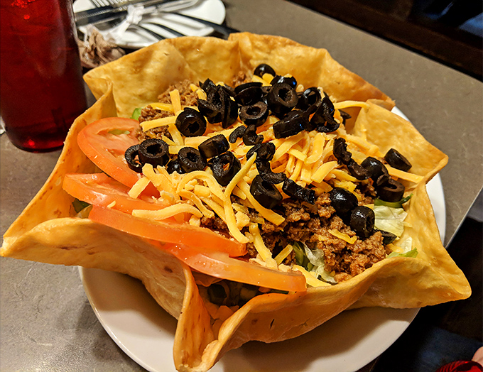 Behold the legendary taco salad – a crispy fortress of tortilla cradling a kingdom of seasoned beef, cheese, olives, and vegetables that's worth crossing county lines for.