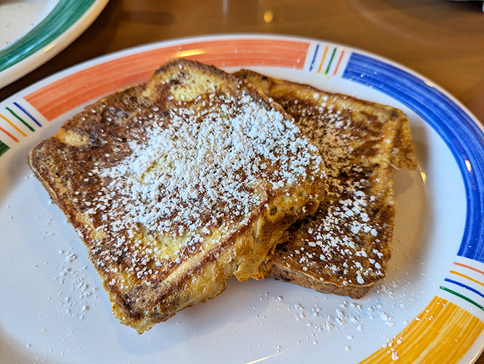 French toast dusted with powdered sugar sits like a sweet island waiting to be explored with fork and knife.