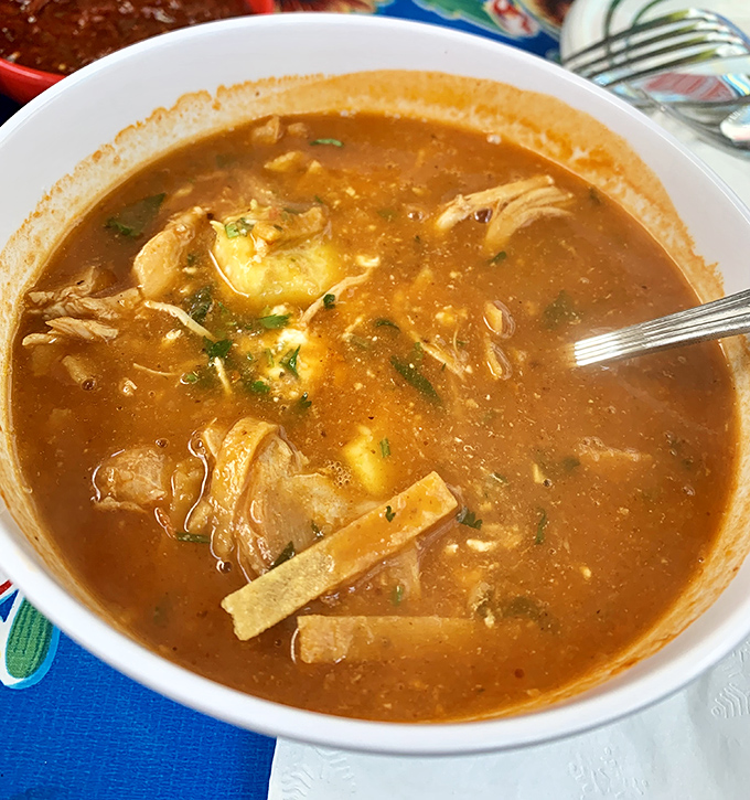 A bowl of tortilla soup so hearty it should come with its own ZIP code. Those chunks of avocado are basically floating islands of joy.