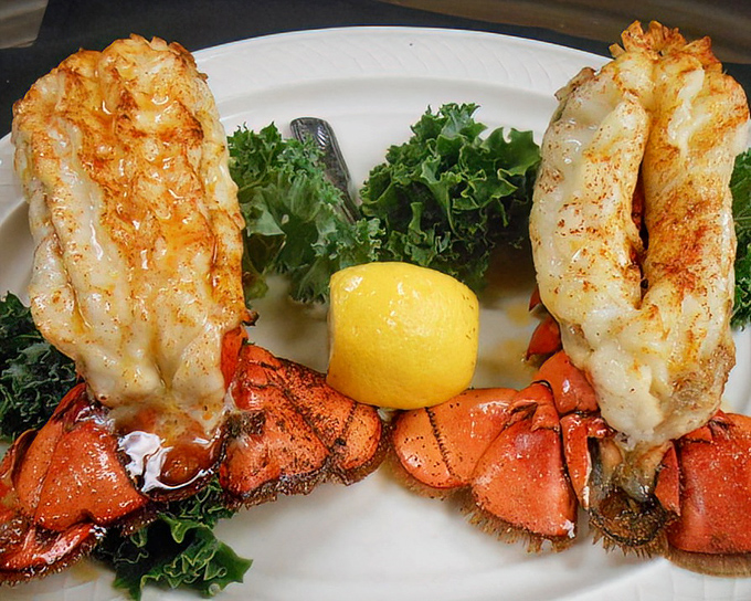 Twin lobster tails perched like royalty on a bed of greens &ndash; Neptune himself would approve of this oceanic treasure.