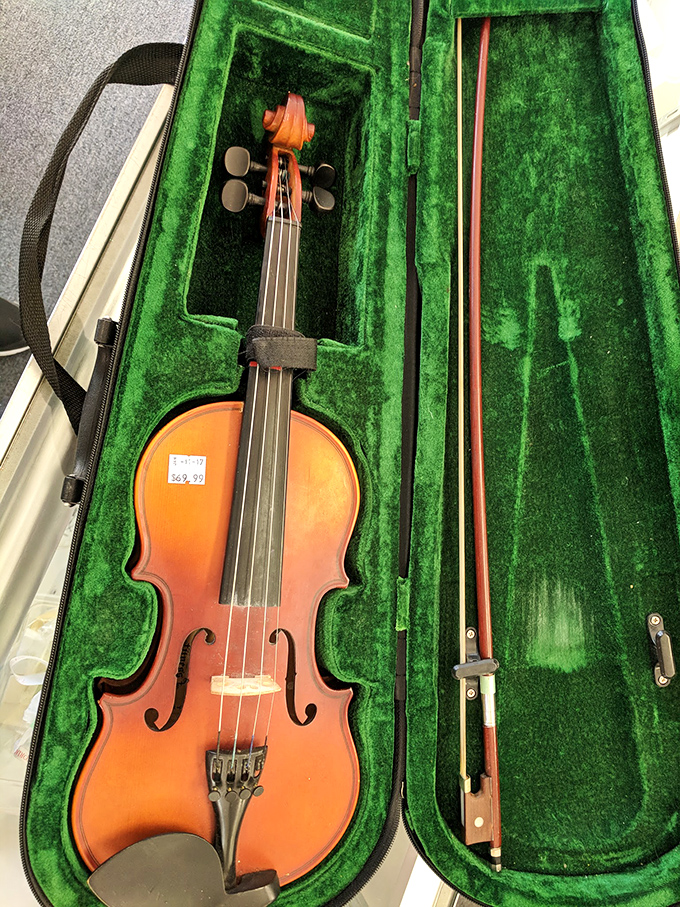 A violin nestled in emerald velvet, ready for its second act—proof that sometimes the most beautiful music comes from instruments with a history.