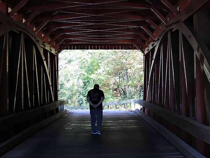 The bridge creates natural frames for contemplation. Here, a visitor pauses to absorb 150 years of history in one quiet moment.