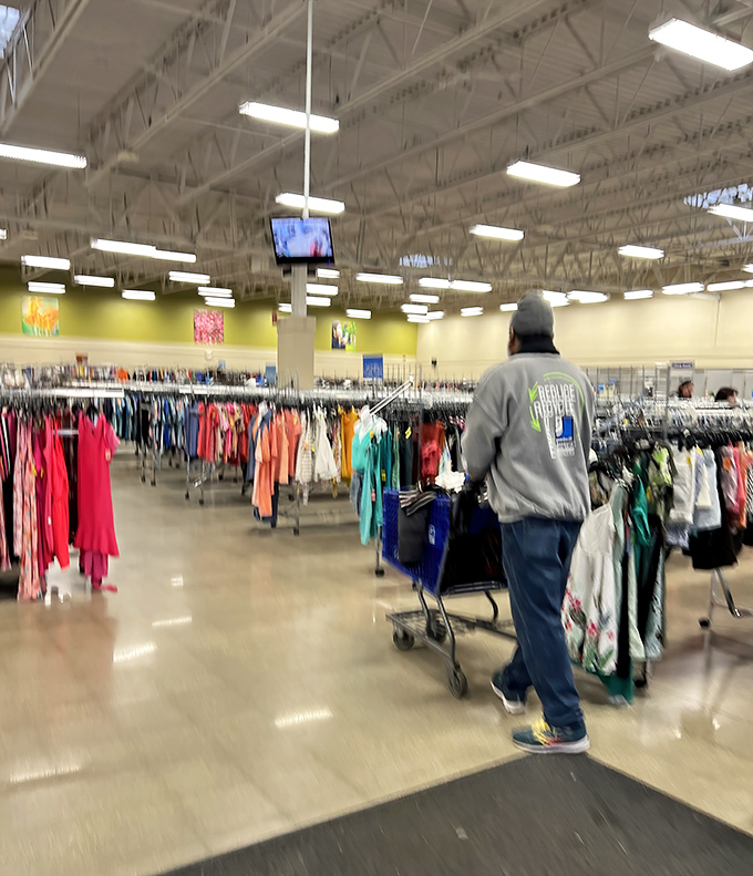 Shoppers navigate the colorful clothing jungle with blue carts, each one a vessel waiting to be filled with someone else's former treasures.