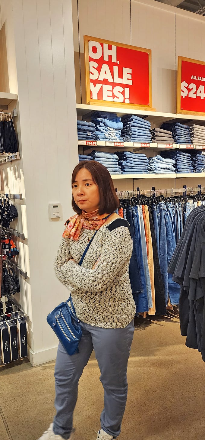 Shopping concentration at its finest. That "Should I splurge?" internal debate plays out silently beneath bright sale signs and neatly folded denim.