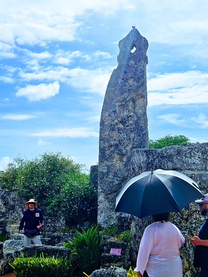 Visitors gather beneath the obelisk, umbrellas providing shade while minds are left exposed to the bewildering questions this place raises.
