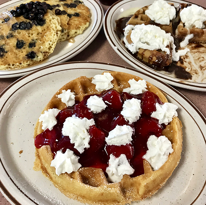 Breakfast's holy trinity: golden blueberry pancakes, chocolate-studded waffles, and a cherry-topped creation that would make dessert jealous.