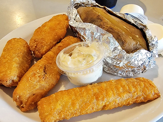 Golden-fried walleye and crispy appetizers share the plate in perfect harmony. That foil-wrapped potato is the silent hero of this delicious ensemble.