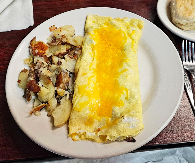This isn't just an omelet&mdash;it's breakfast architecture, with perfectly folded eggs cradling melted cheese alongside home fries that deserve their own zip code.