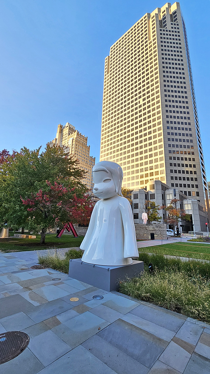 The serene "White Ghost" sculpture stands in stark contrast to the urban backdrop, like a peaceful visitor from another dimension.