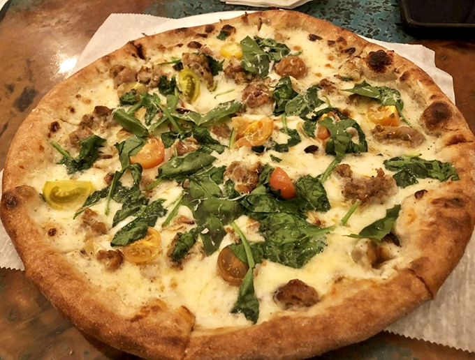 This isn't just pizza—it's a garden party on dough. Those fresh greens and heirloom tomatoes are having the time of their lives.