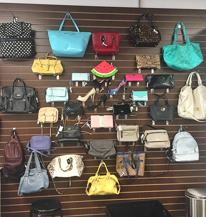 The handbag wall—a museum of previous lives where designer dreams hang waiting for their second chance at fashion glory.