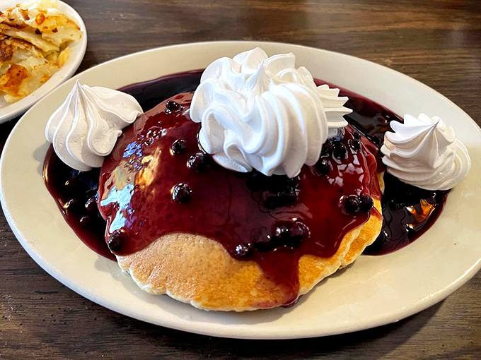 Blueberry pancakes crowned with whipped cream and swimming in purple syrup—proof that sometimes the most photogenic food is found in the most unpretentious places.