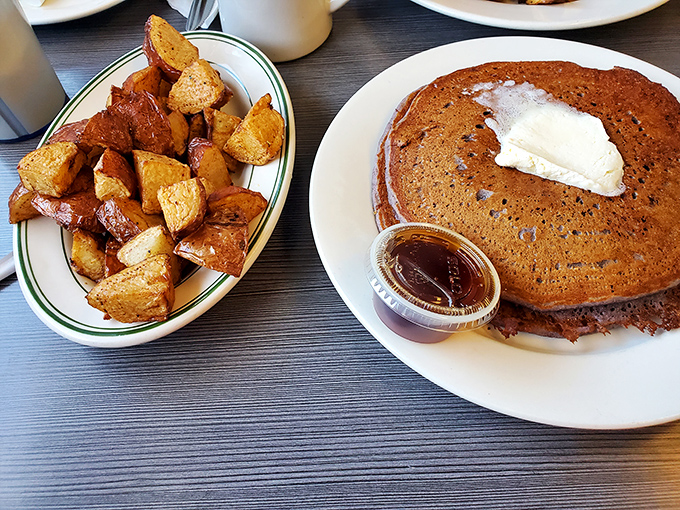 A pancake with a pat of butter melting into its warm embrace, alongside crispy home fries&mdash;this isn't just breakfast, it's morning therapy.