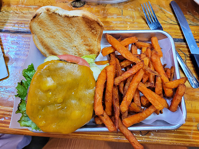 Behold the classic American cheeseburger in its natural habitat &ndash; juicy patty, melted cheese, and those sweet potato fries that somehow make you feel virtuous.