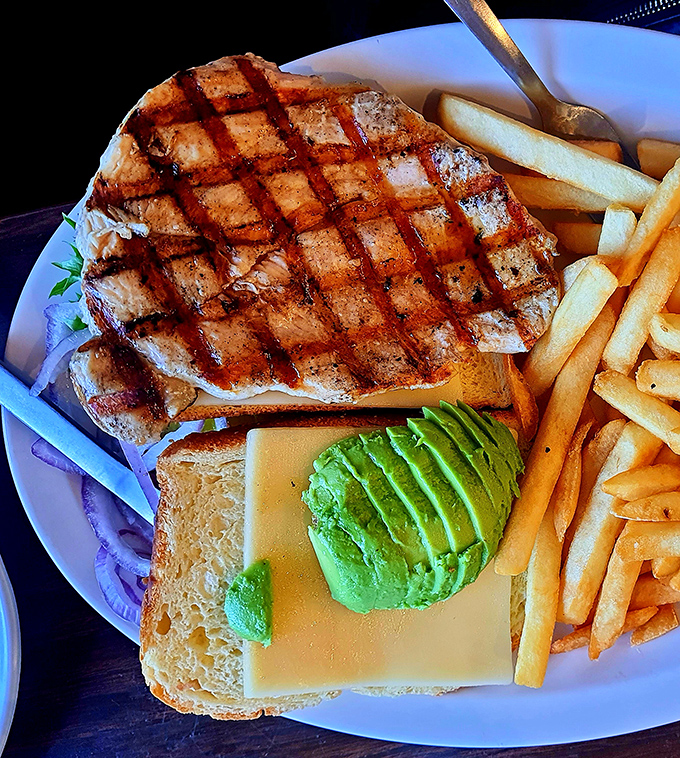 A sandwich that requires strategic planning before the first bite &ndash; note the perfect grill marks and the avocado standing at attention.