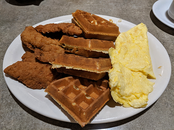 The holy trinity of breakfast comfort: golden waffles, crispy chicken, and fluffy eggs. A plate that says "good morning" with authority.