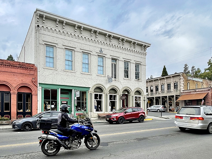 The elegant white building stands in stark contrast to its red brick neighbors – architectural diversity that somehow creates perfect small-town harmony.