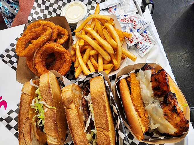 The holy trinity of diner perfection: golden fries, crispy onion rings, and sandwiches that require both hands and several napkins. Worth every delicious calorie.