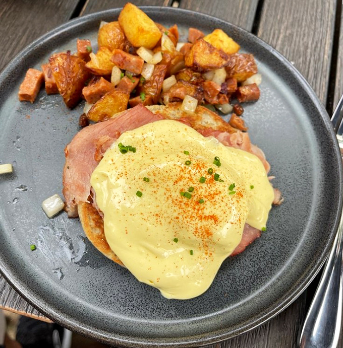 Eggs Benedict reimagined: a golden hollandaise blanket tucked over ham and English muffin, with home fries playing the perfect supporting role.