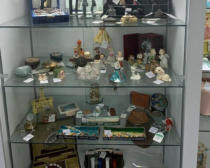 These glass-encased figurines silently wait for their stories to continue in new homes, each tiny face holding decades of memories.