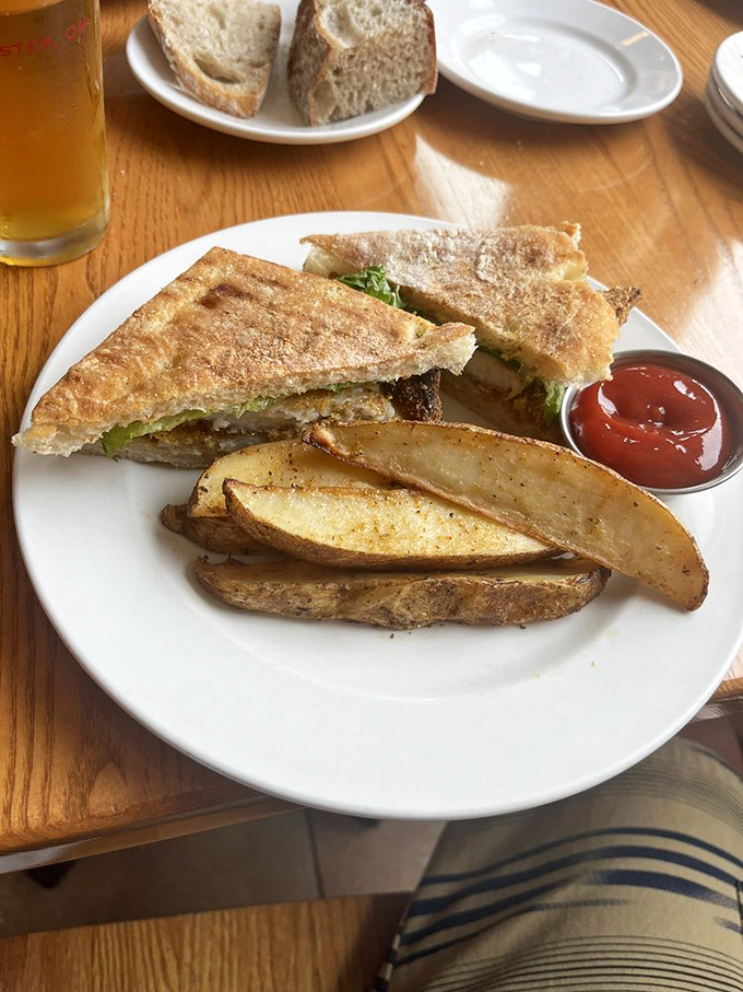 The humble sandwich, elevated to art form—crispy potato wedges standing guard beside a creation that puts lunch boxes everywhere to shame.