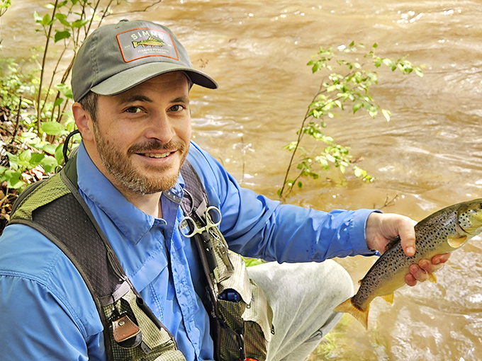One happy angler shows off his catch, proving that patience and a fishing vest really do pay off.