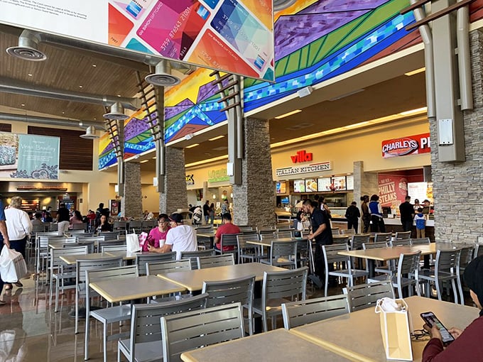 The food court's colorful canopy hovers above hungry shoppers like a rainbow of retail therapy, with Charley's Philly Steaks standing by for sustenance.