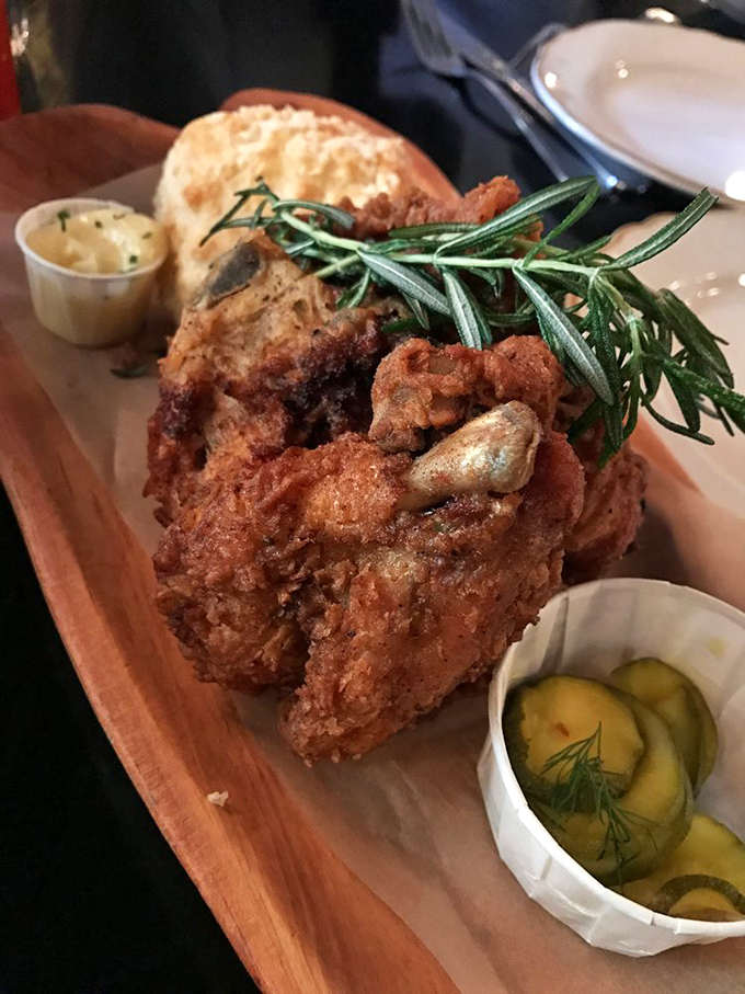 Fried chicken perfection: golden-brown armor protecting juicy meat within, accompanied by house-made pickles that cut through the richness brilliantly.