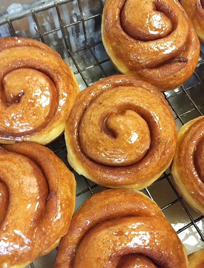 Fresh honeybuns await their chocolate baptism&mdash;the spiral design isn't just pretty, it creates perfect pockets where that sweet glaze can pool into flavor nirvana.