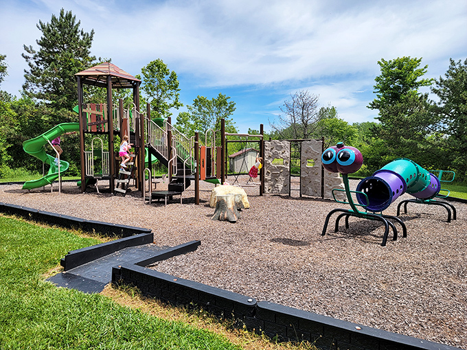 Colorful playground equipment stands ready for adventure, complete with a friendly caterpillar sculpture that would make Eric Carle proud.
