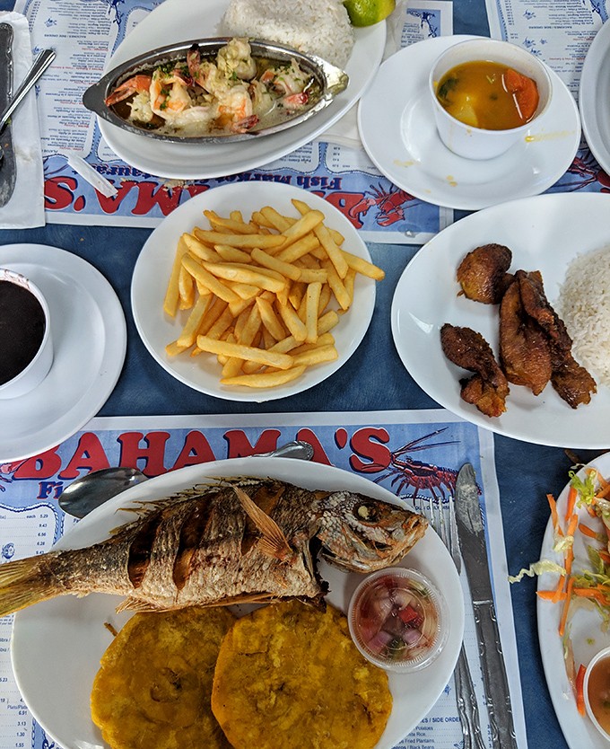 A feast fit for Neptune himself! Fried fish, plantains, rice, and all the fixings spread across the table like an edible mosaic of Caribbean flavors.