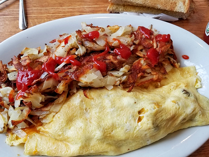 The omelet that launched a thousand road trips. Perfectly folded egg blanket cradling a mountain of fillings with hashbrowns that deserve their own fan club.