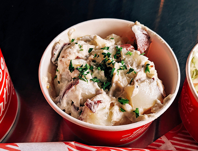 Creamy potato salad in its red-rimmed cup isn't just a side&mdash;it's the cooling diplomat negotiating peace between your taste buds and that fiery chicken.