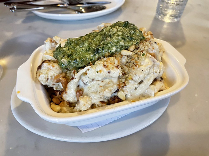 Roasted cauliflower transformed from humble vegetable to star attraction, crowned with vibrant pesto and toasted pine nuts.