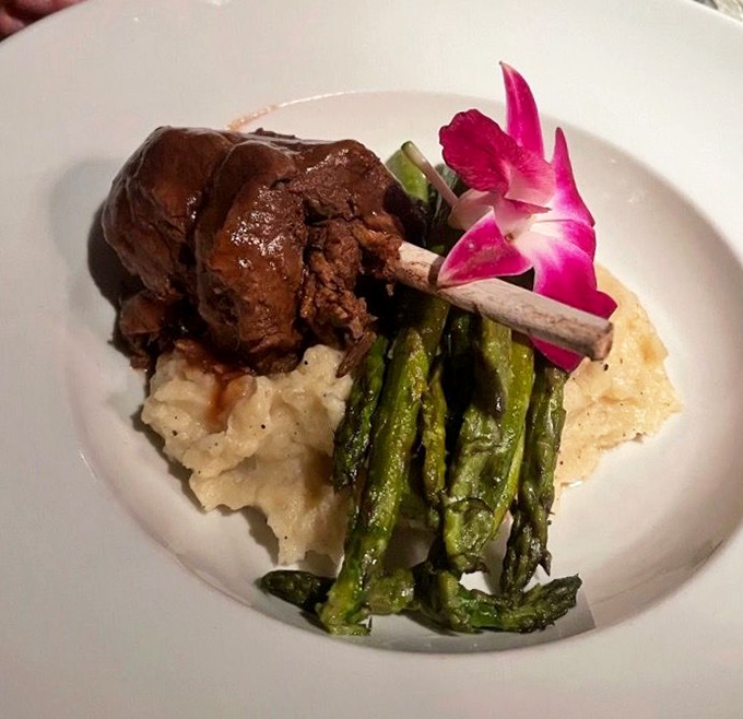 Behold the star attraction: fork-tender short ribs nestled on creamy grits with asparagus, where four hours of patience transforms into one unforgettable meal.