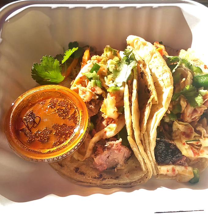 Korean-Southern fusion at its finest &ndash; barbecue tacos with kimchi slaw and cilantro. The sauce cup is practically begging you to dip.