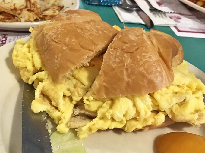 Breakfast architecture at its finest: golden eggs spilling from a buttery croissant, creating the sandwich that would make any morning person weak at the knees.