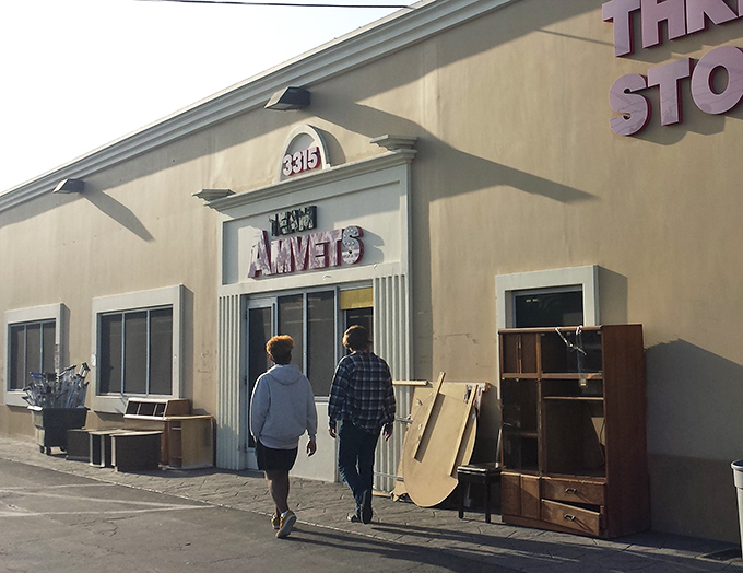 Two shoppers approach thrift nirvana, where furniture patiently waits outside like eager dogs hoping to find their forever homes.