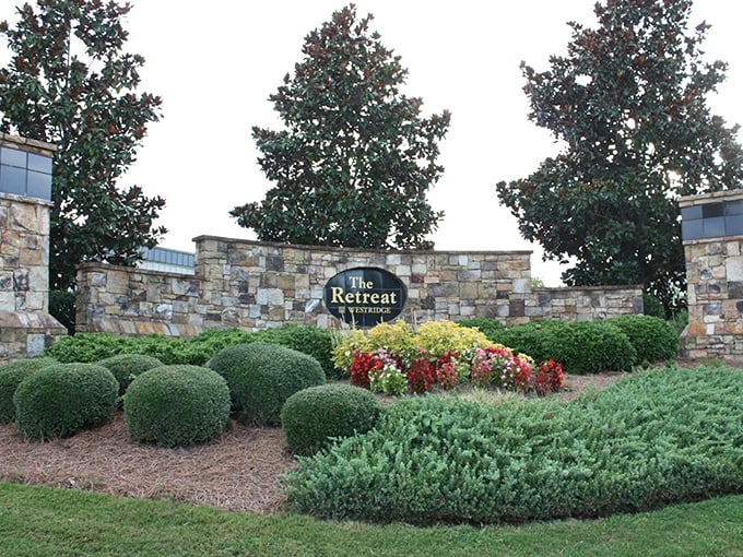 The Retreat's entrance sign nestled among perfectly shaped shrubs. First impressions matter, and this one says "upscale living."
