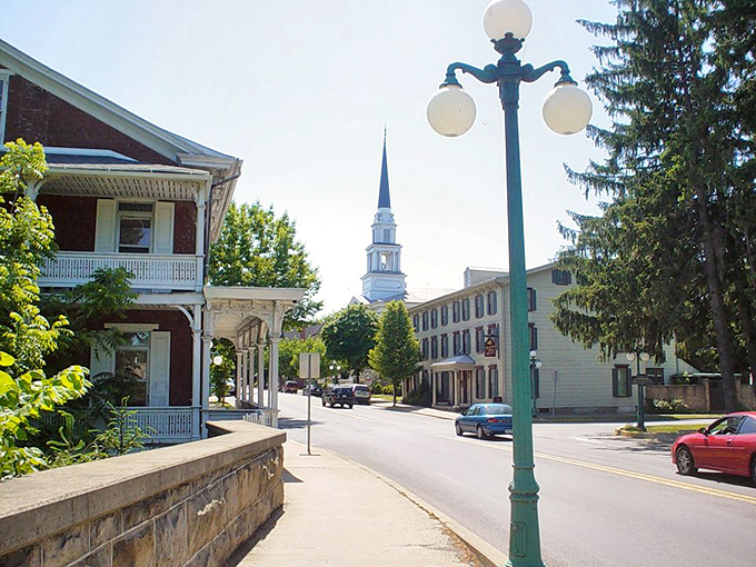Lewisburg's tree-lined streets feature vintage lampposts, historic buildings, and a white church steeple rising majestically against the blue sky.