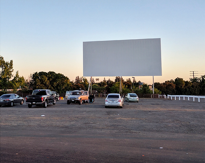 Sacramento's twilight transforms ordinary vehicles into private screening rooms, where the white picket fence seems to say, "This is Americana at its finest."