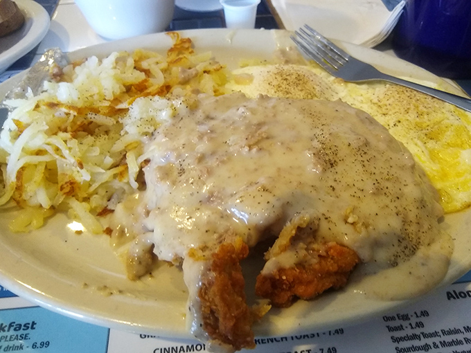 Country-fried steak swimming in gravy alongside hash browns and eggs—a plate that says "you won't need lunch" in the most delicious way.