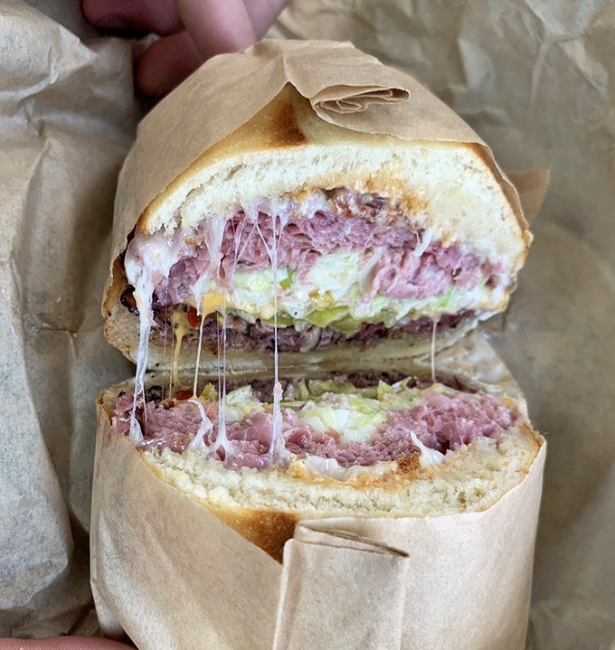 This cross-section reveals the architectural marvel within &ndash; pastrami stacked like edible skyscrapers between pillows of fresh bread.