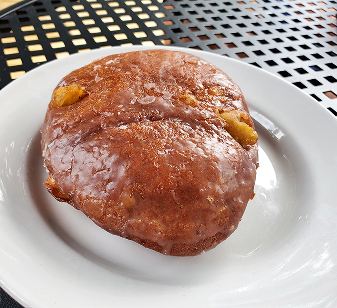This apple fritter isn't just a donut&mdash;it's a glistening monument to morning indulgence, with chunks of apple hiding like buried treasure beneath that crackling glaze. 