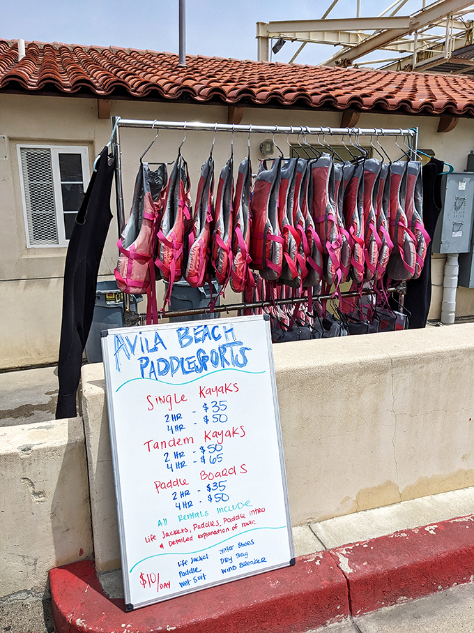 Kayak rentals lined up like colorful chariots awaiting adventure. The ocean's calling – will you answer with a single or tandem paddle?