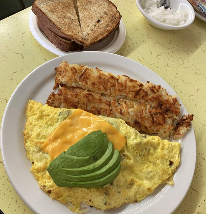 The California dream in omelet form: perfectly folded eggs embracing melted cheese and fresh avocado slices that make kale smoothies jealous.