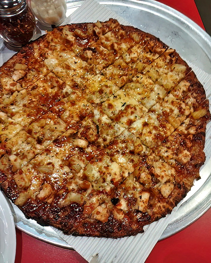 The BBQ Chicken Pizza sits regally in its delivery throne, ready to challenge your notion that traditional toppings are the only path to pizza nirvana.