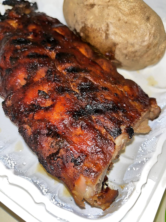 These baby back ribs wear their caramelized glaze like a badge of honor. That baked potato standing guard knows it's in distinguished company.